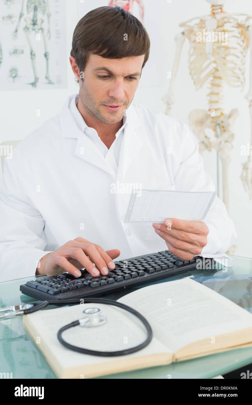 Doctor reading a note at desk in medical office Stock Photo - Alamy