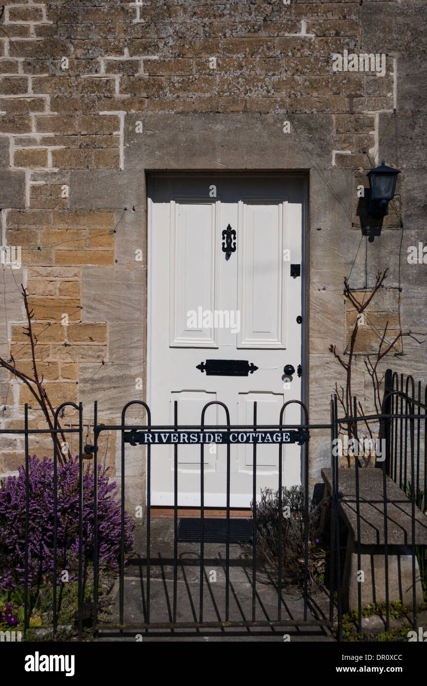 Traditional Cotswolds stone cottage. Closed white front door. Lower ...