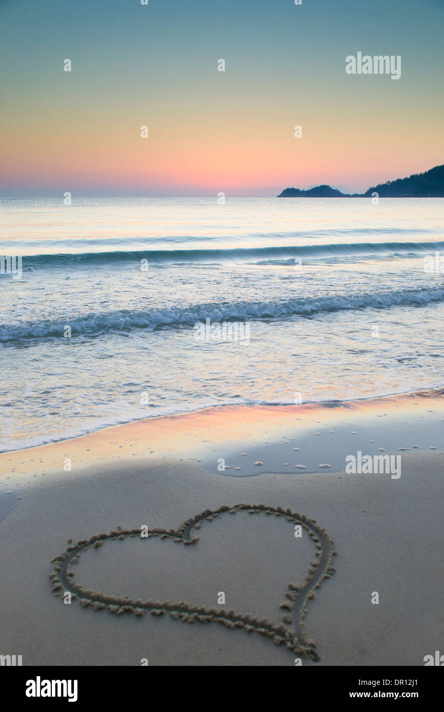 Heart shape drawn on a sandy beach at sunrise on the beautiful island ...
