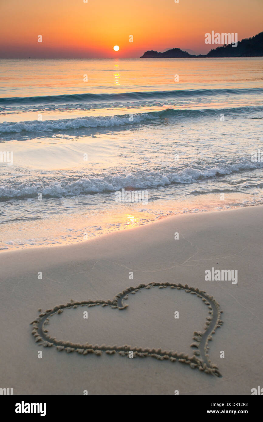Heart shape drawn on a sandy beach at sunrise on the beautiful island ...