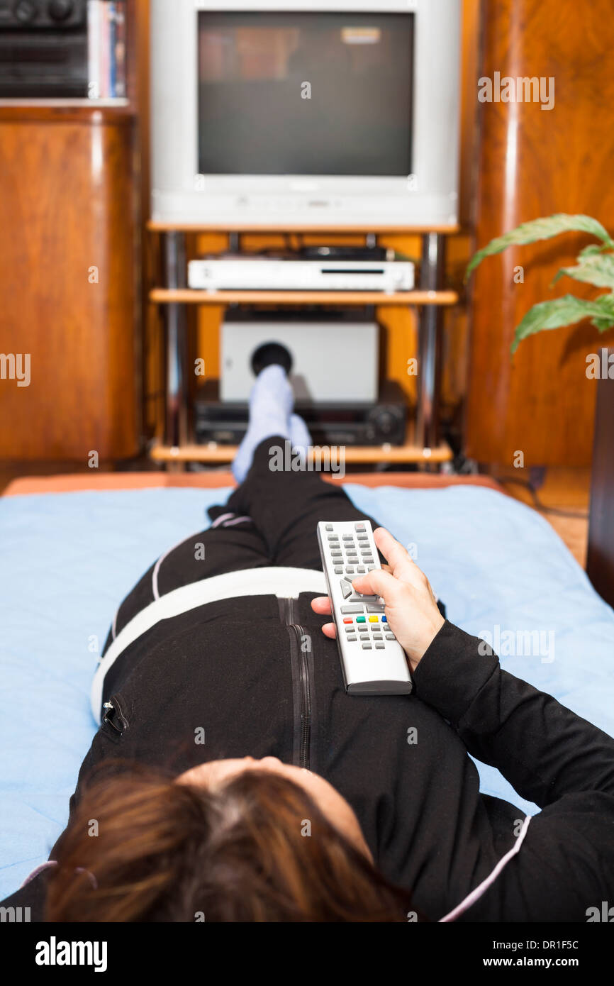 Middle aged woman with remote control watching TV at home. Shallow ...