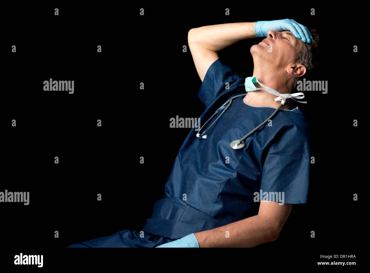 Tired doctor in uniform in a dark background Stock Photo - Alamy