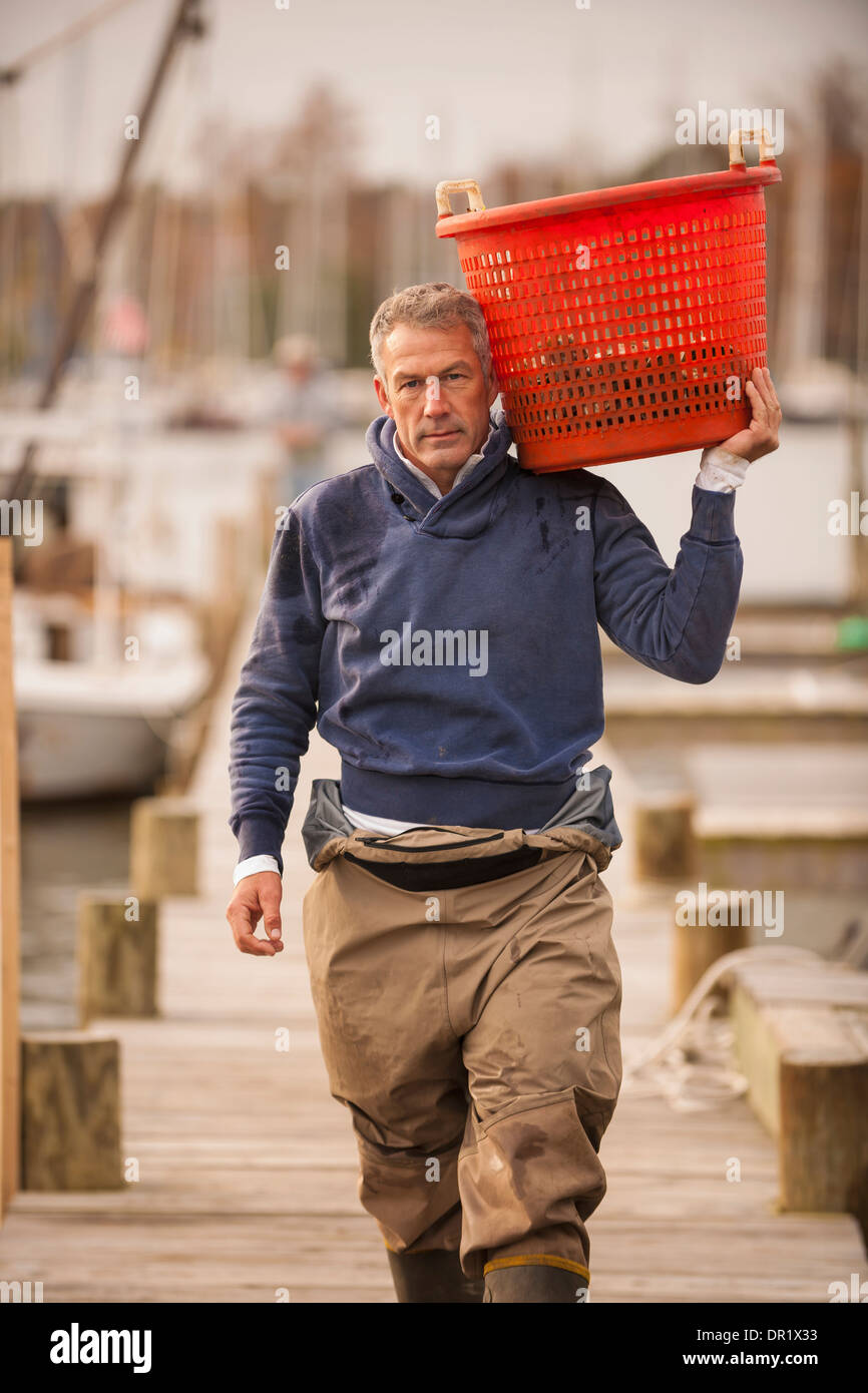 Caucasian fisherman carrying basket on dock Stock Photo - Alamy