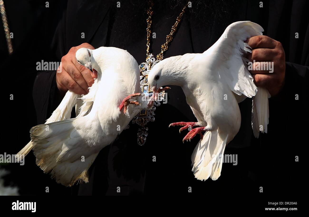 Amman. 17th Jan, 2014. A Christian priest holds two doves during Mass ...