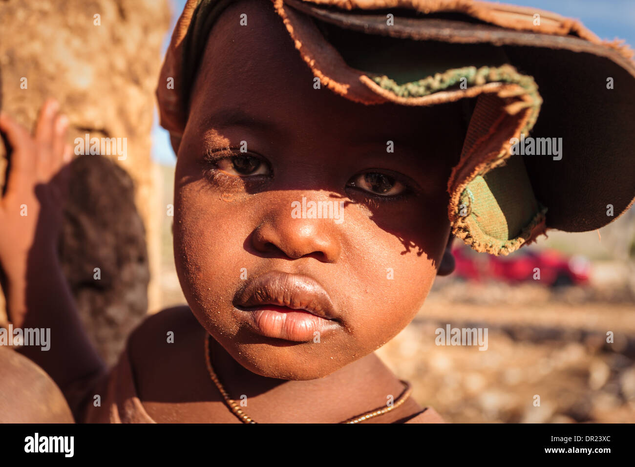 Portrait of face of Himba child with two hats on in Damaraland, Namibia ...