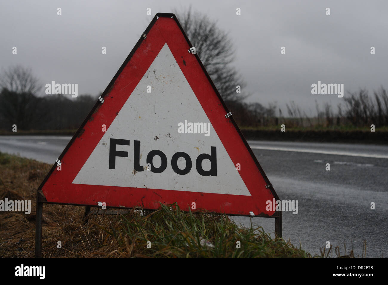 A flood sign at the side of a road during heavy rain during a sever ...