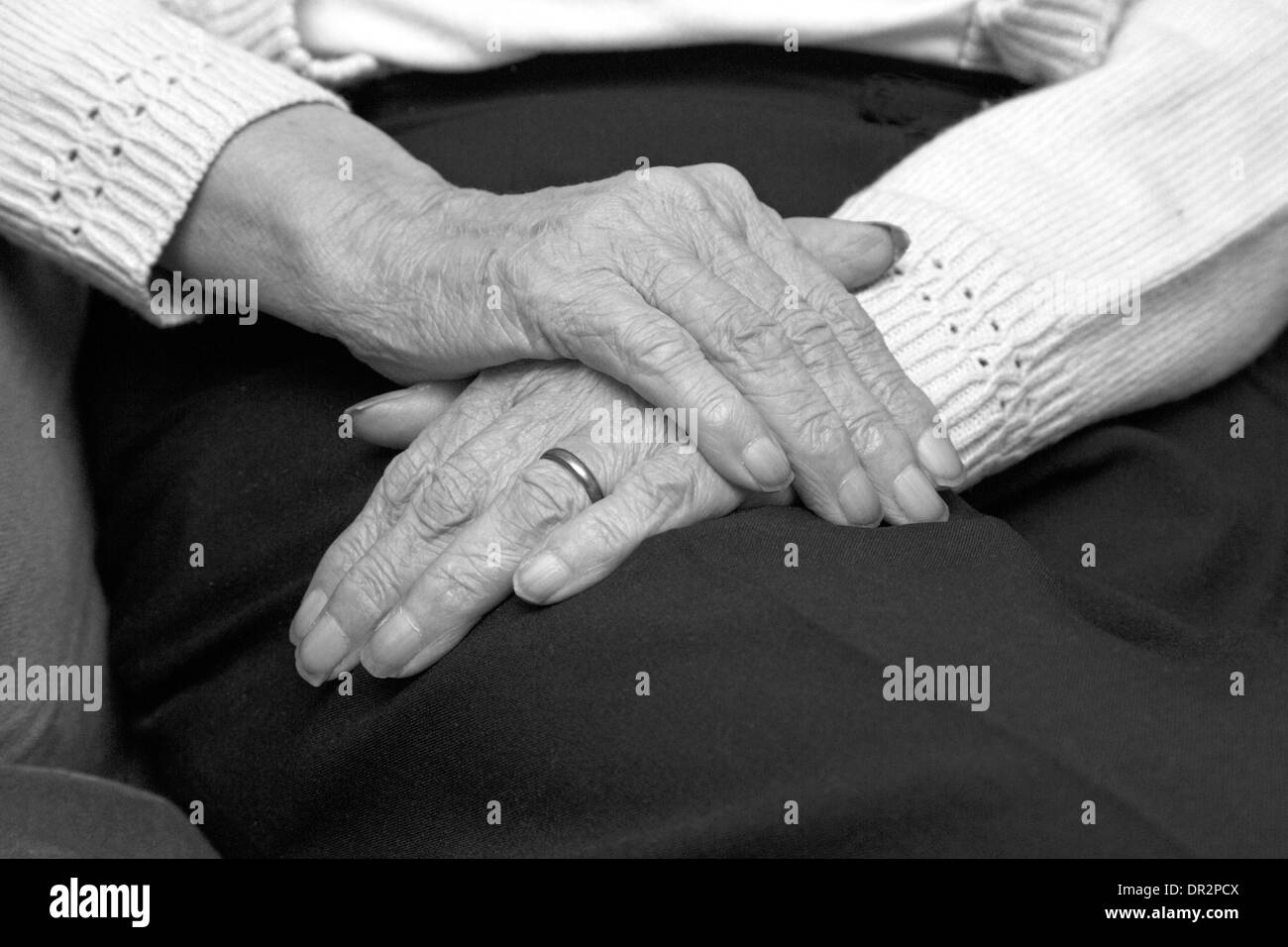 Old lady with one hand over the other resting on her lap also wearing a ...