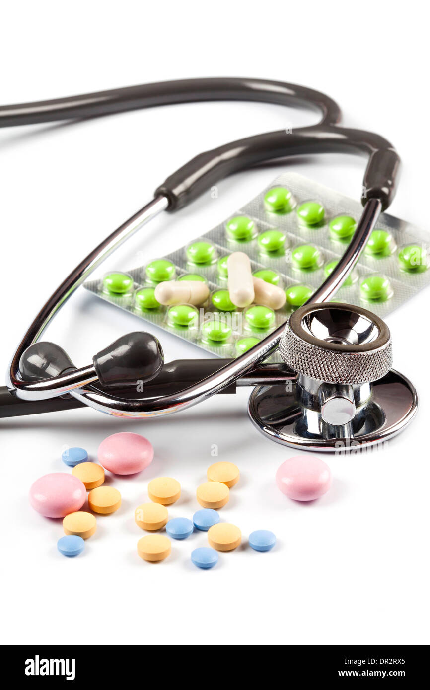Multi color pills spills around the stethoscope, one blister with green ...