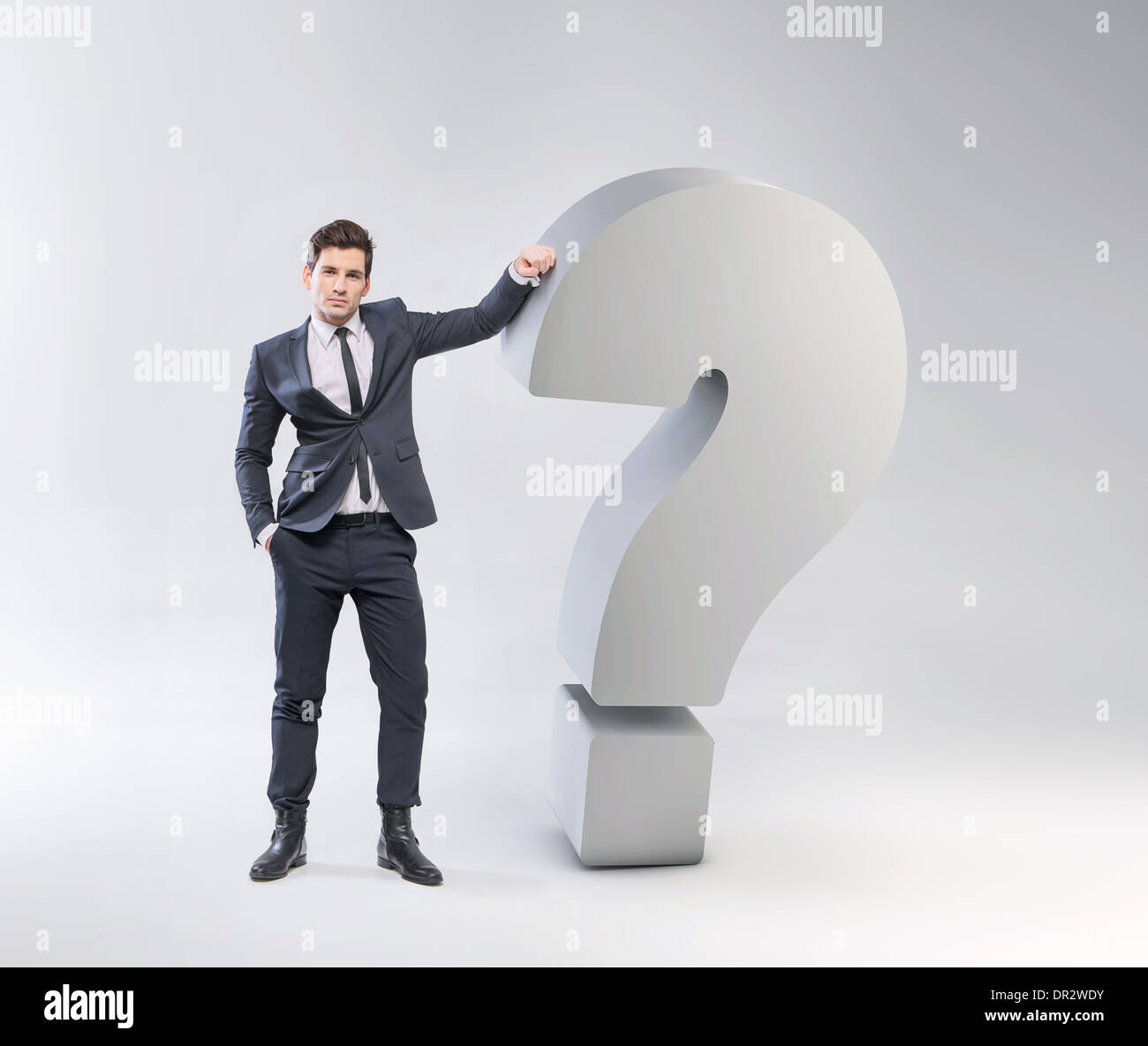 Elegant young man leaning against the huge question mark Stock Photo ...