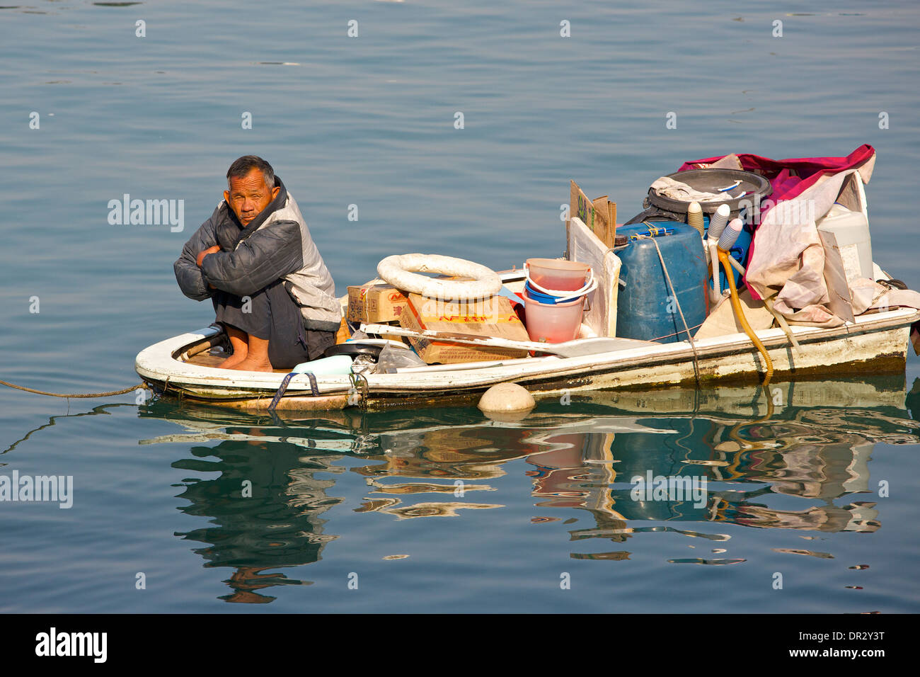 Old Chinese man sits on the bow of an overloaded boat in the Causeway ...