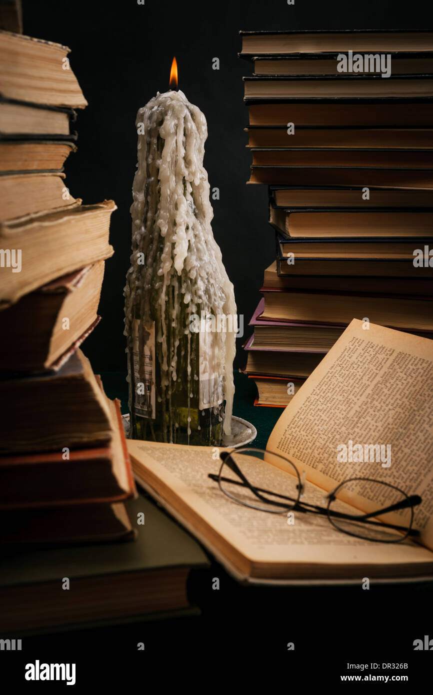 a melting candle in a bottle among old books Stock Photo - Alamy