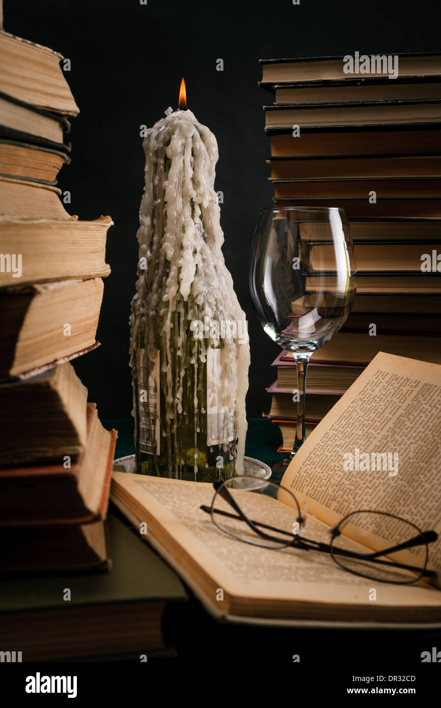 a melting candle in a bottle among old books Stock Photo - Alamy
