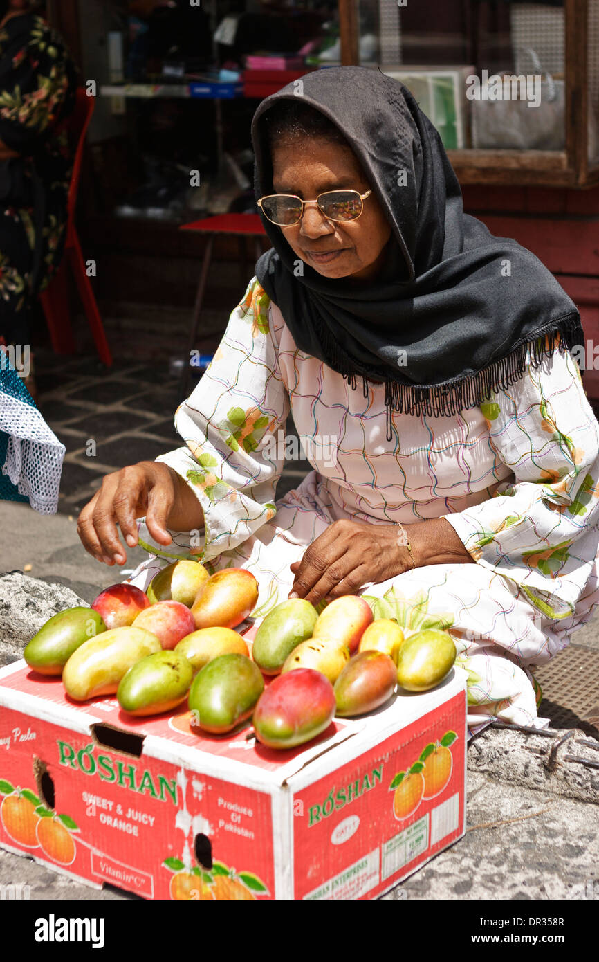 Woman selling ripe mangoes on a cardboard box on the street, Port Louis ...
