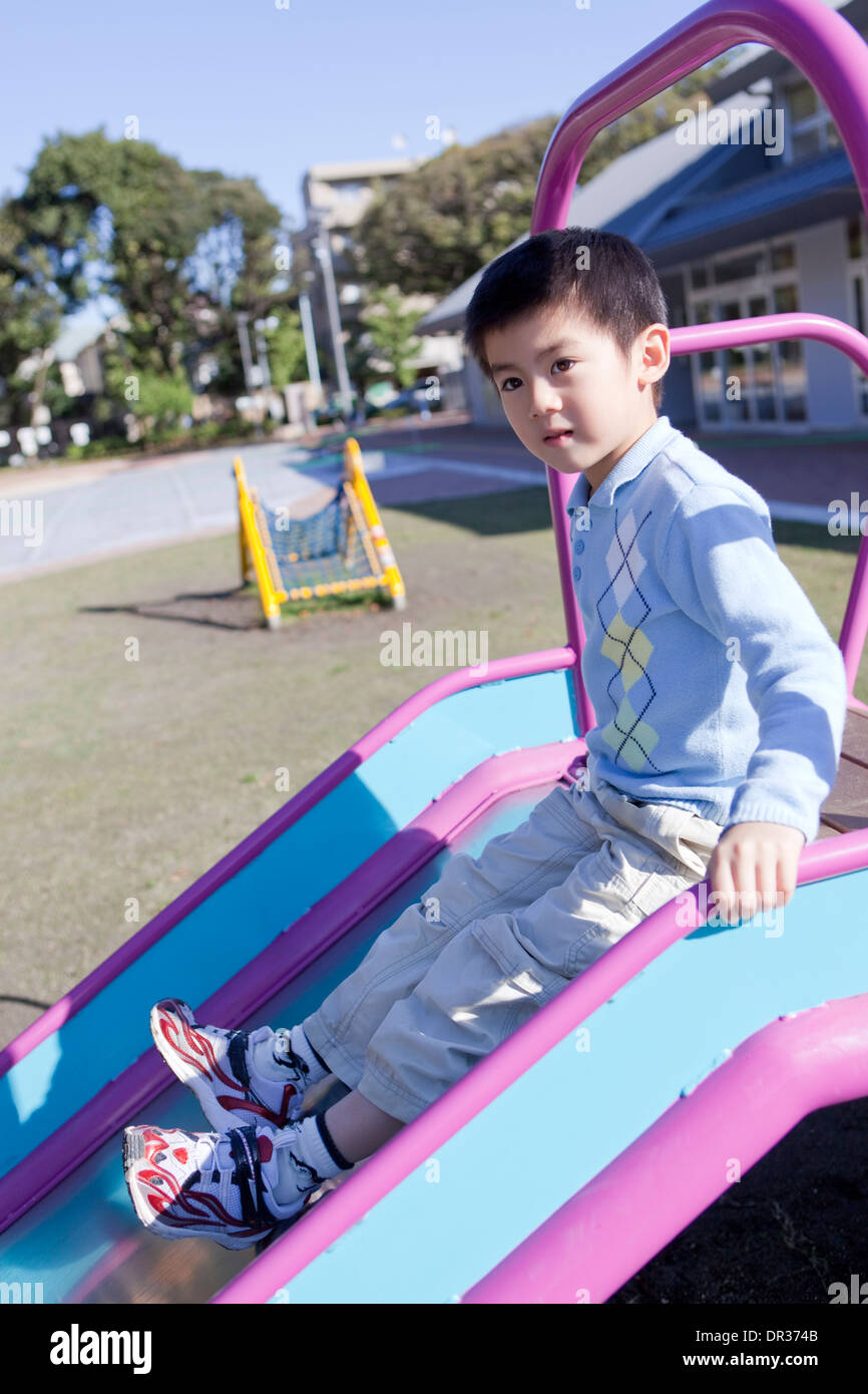 Boy sitting on slide Stock Photo - Alamy