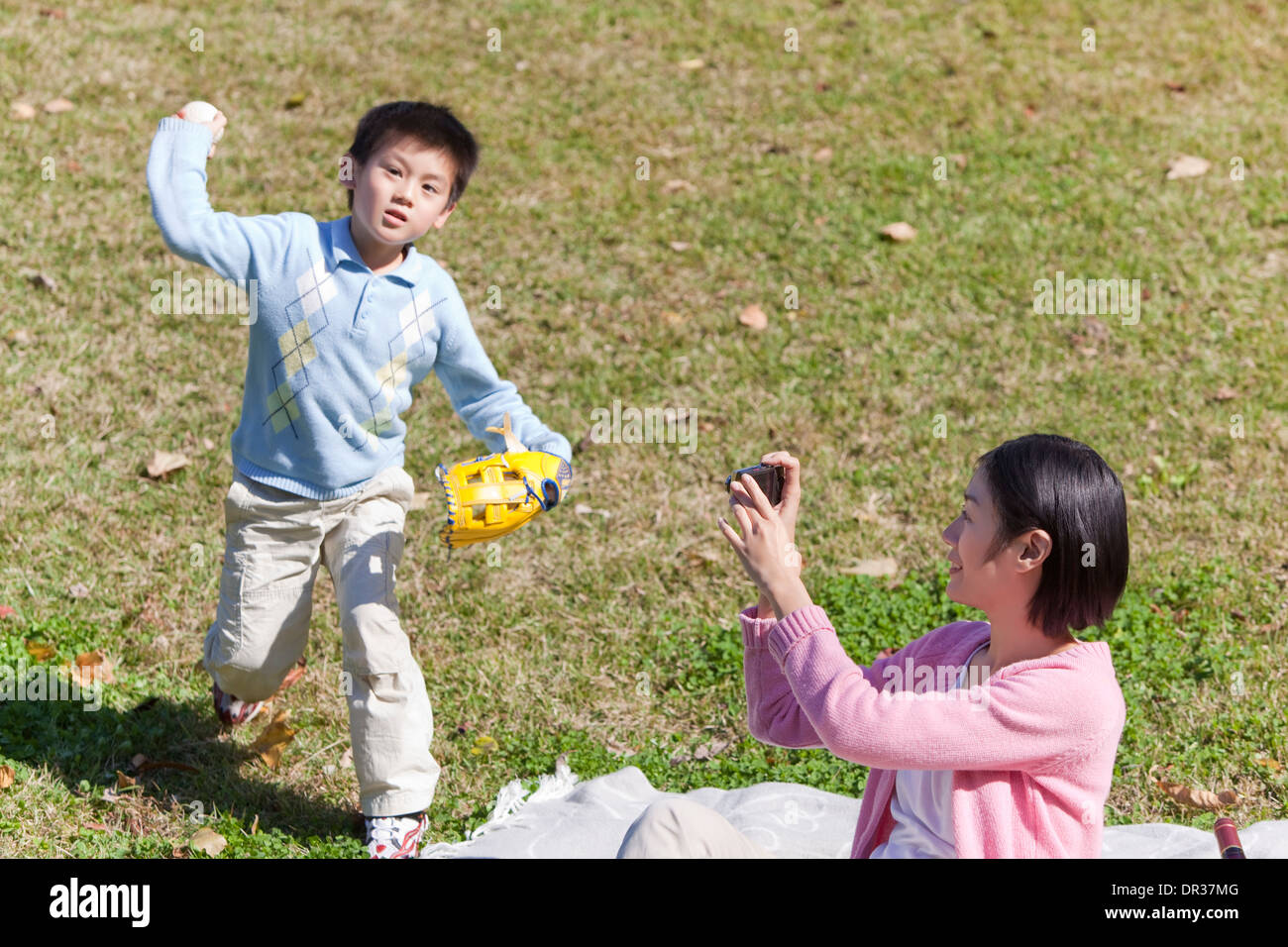 Mother taking photo of son playing catch Stock Photo - Alamy