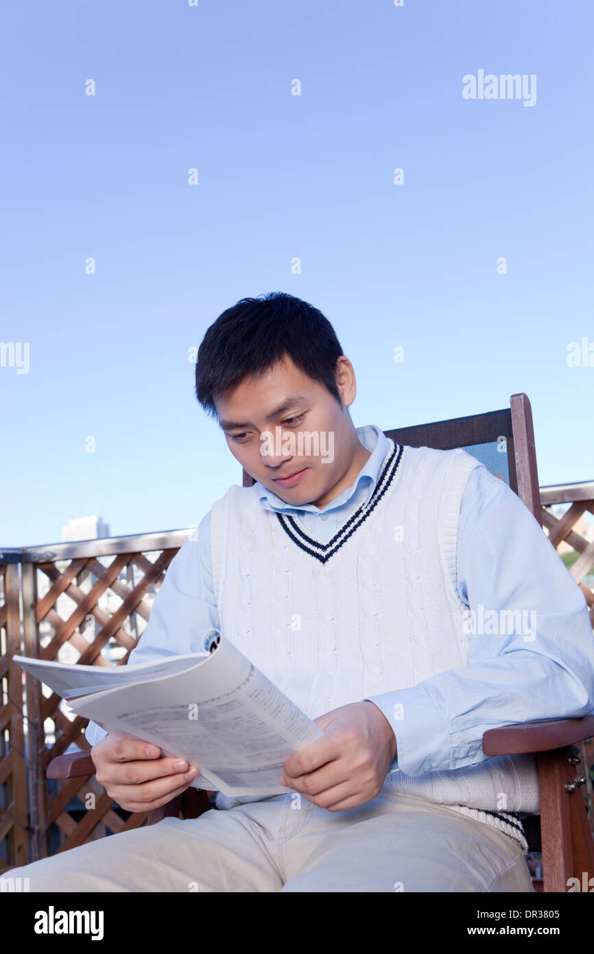 Mid adult man reading magazine Stock Photo - Alamy
