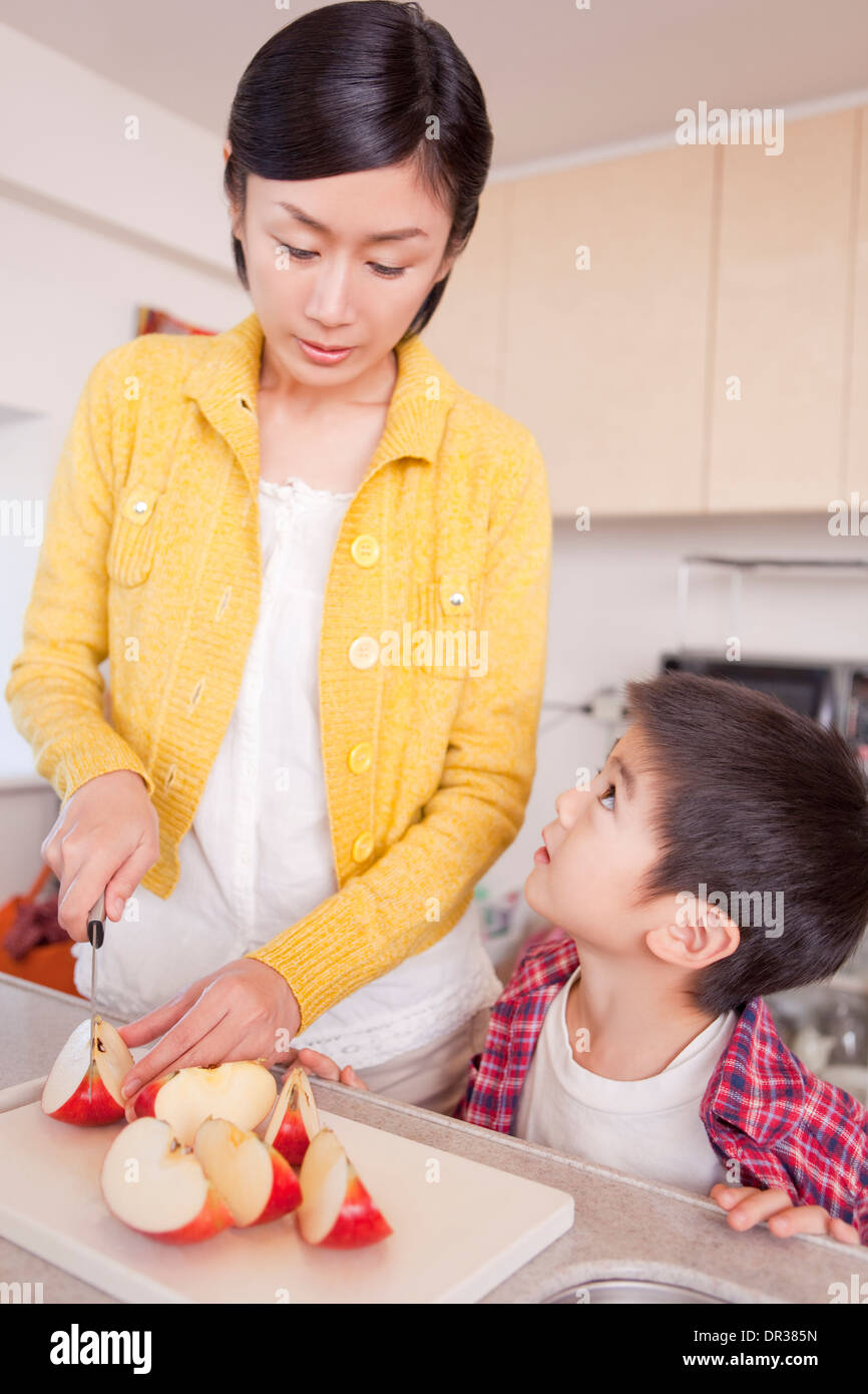 Son watching mother cut apple Stock Photo - Alamy