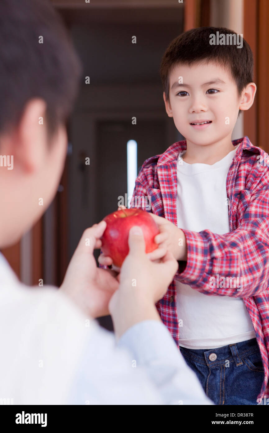 Son giving apple to father Stock Photo - Alamy
