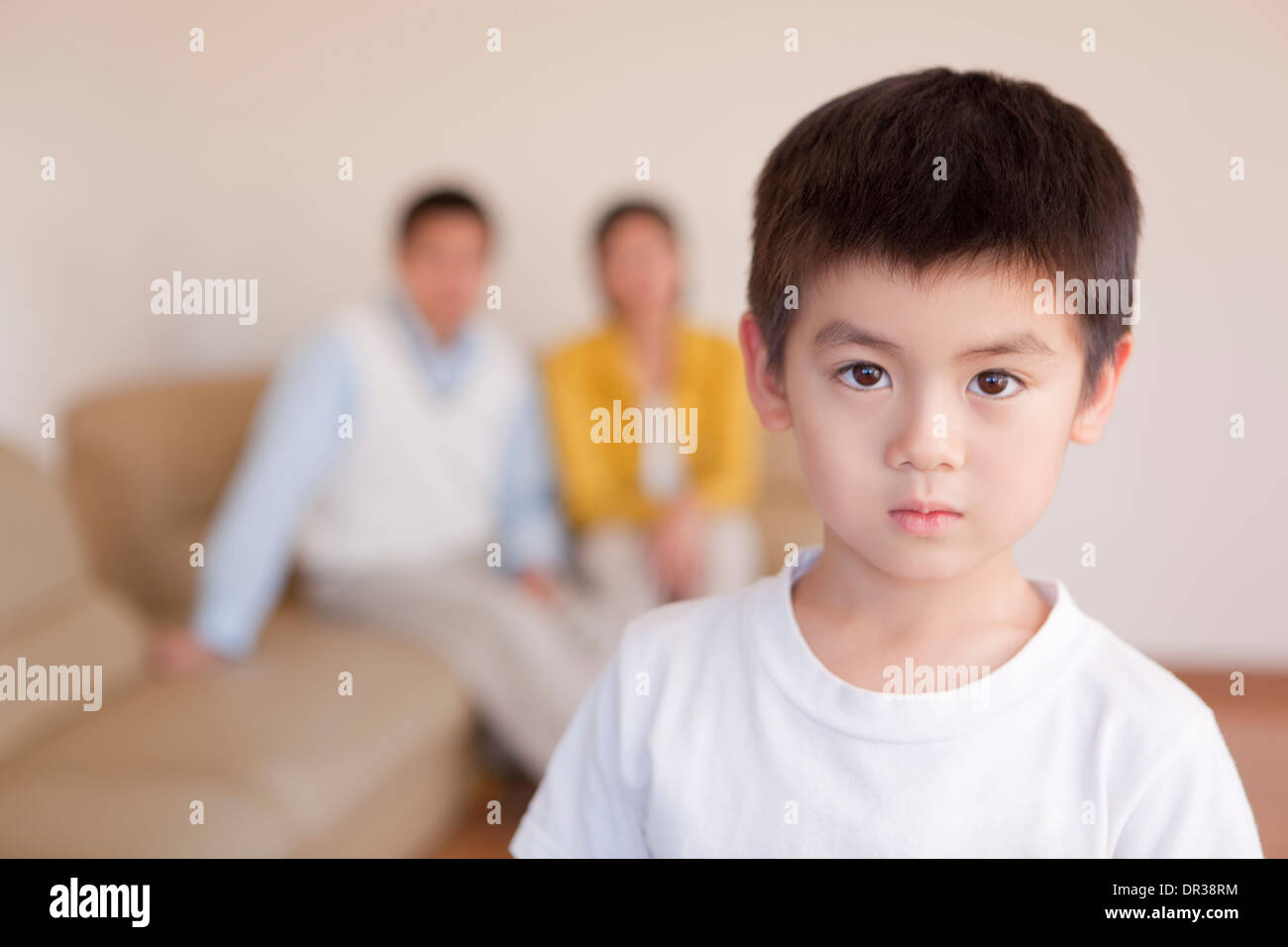 Boy looking at camera, parents in background Stock Photo - Alamy