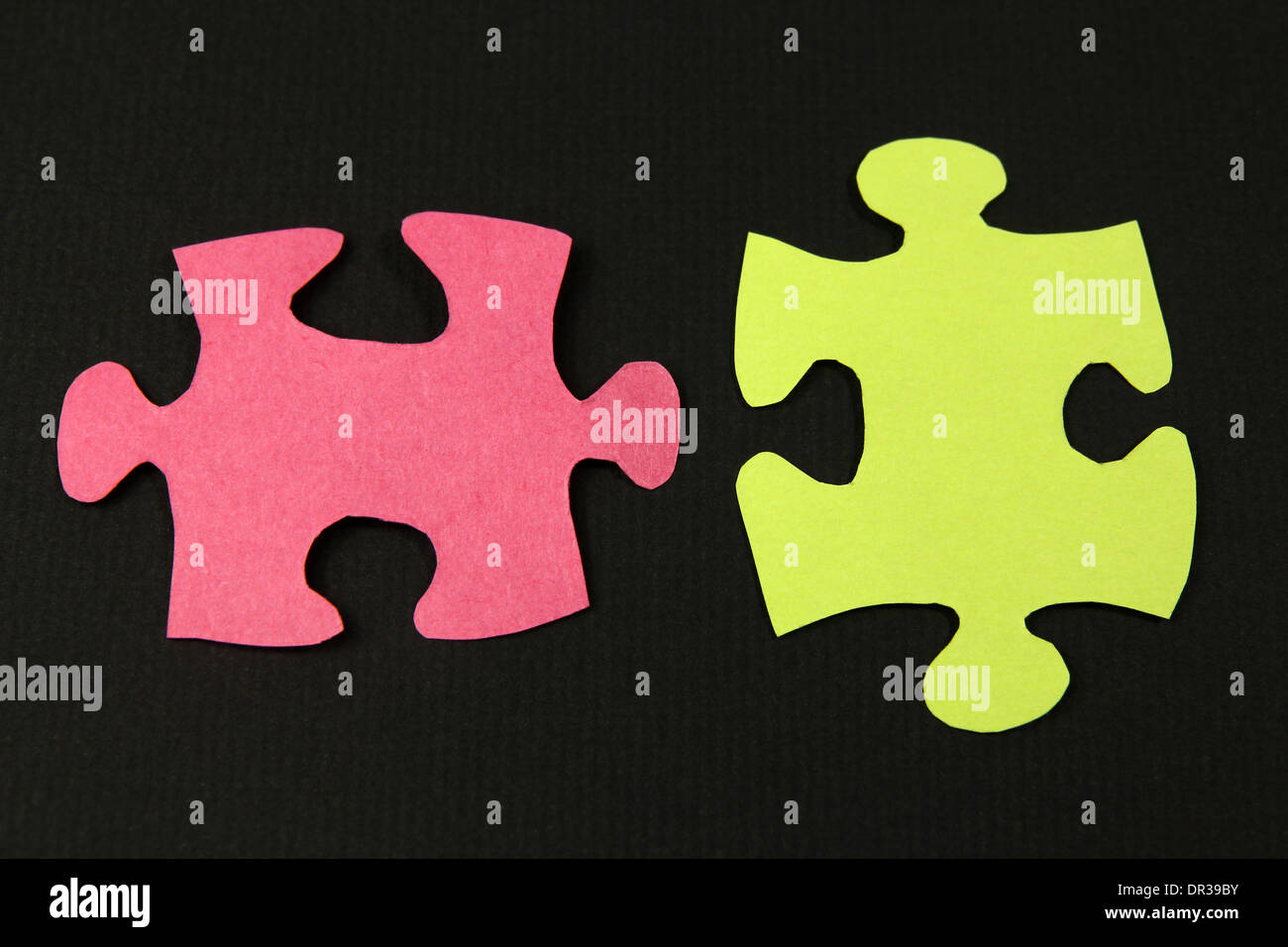 two parts of puzzle on black paper background Stock Photo - Alamy