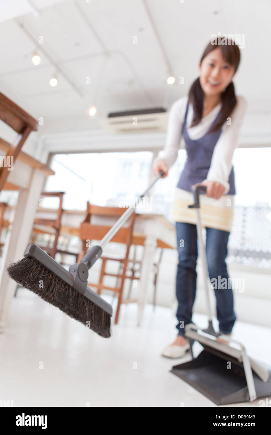 Young woman sweeping floor at café Stock Photo - Alamy
