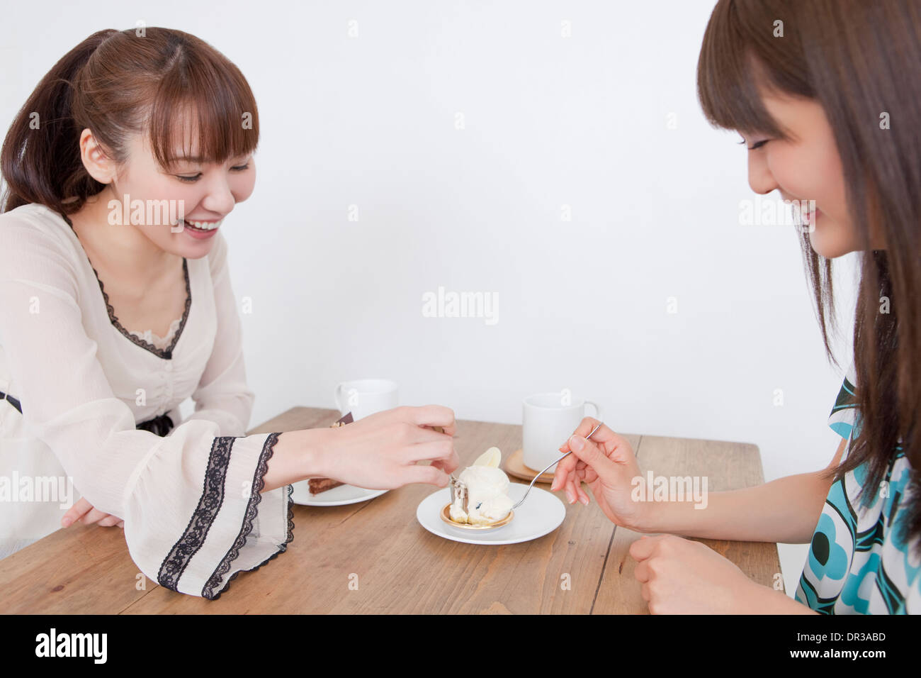 Two young women eating cake Stock Photo - Alamy