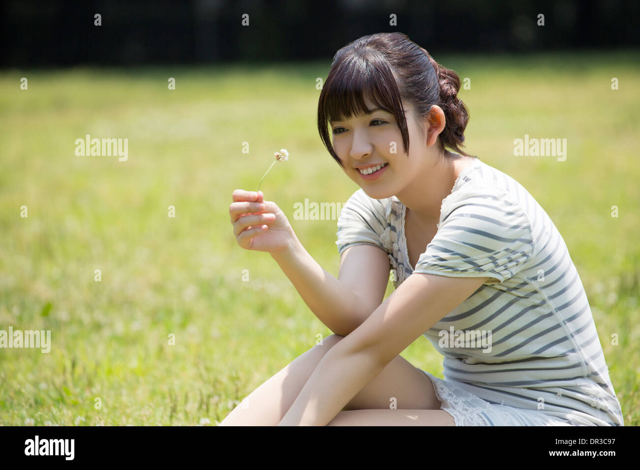 Young woman sitting on lawn Stock Photo - Alamy