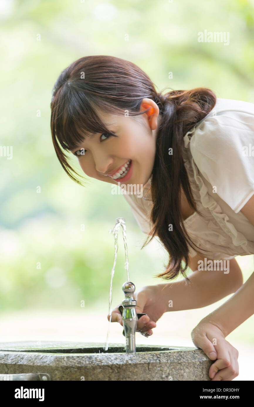 Young woman trying to drink tap water Stock Photo - Alamy