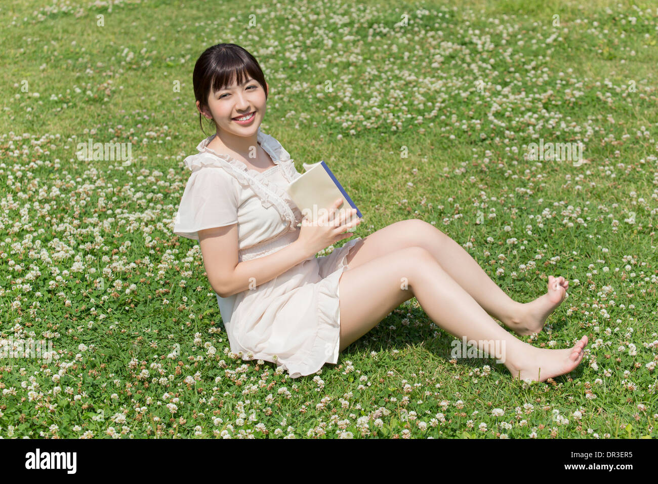 Young woman sitting on lawn Stock Photo - Alamy