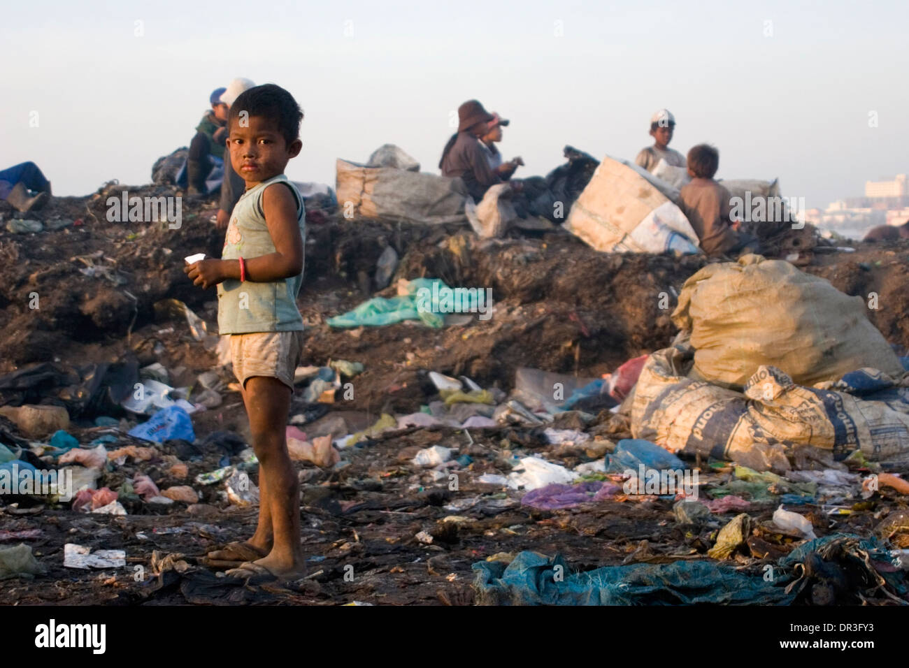 A young child laborer boy is standing in a toxic garbage at the Stung ...