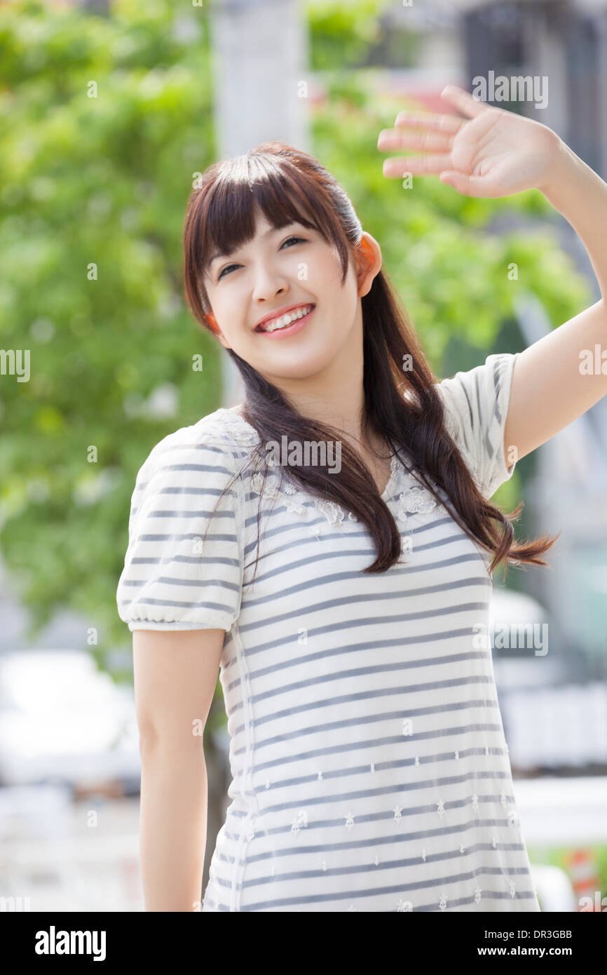 Young woman waving hand Stock Photo - Alamy