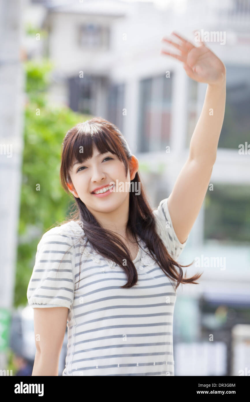 Young woman waving hand Stock Photo - Alamy