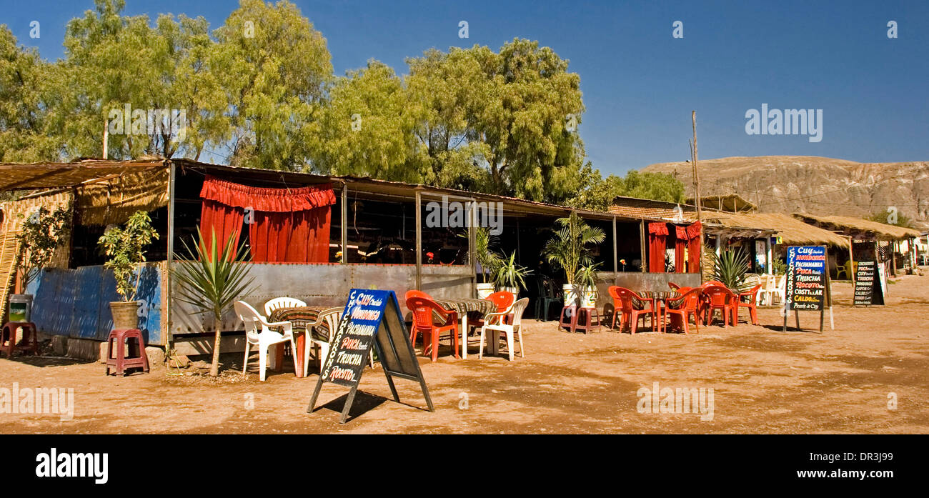 Open air restaurant with red plastic tables and chairs outside ...
