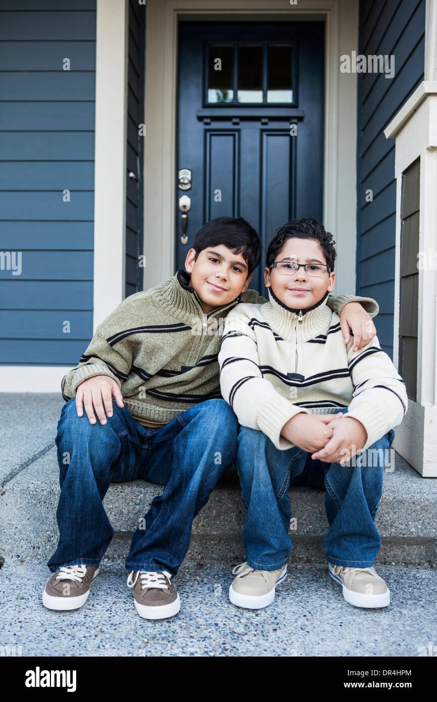Hispanic boys hugging on front stoop Stock Photo - Alamy