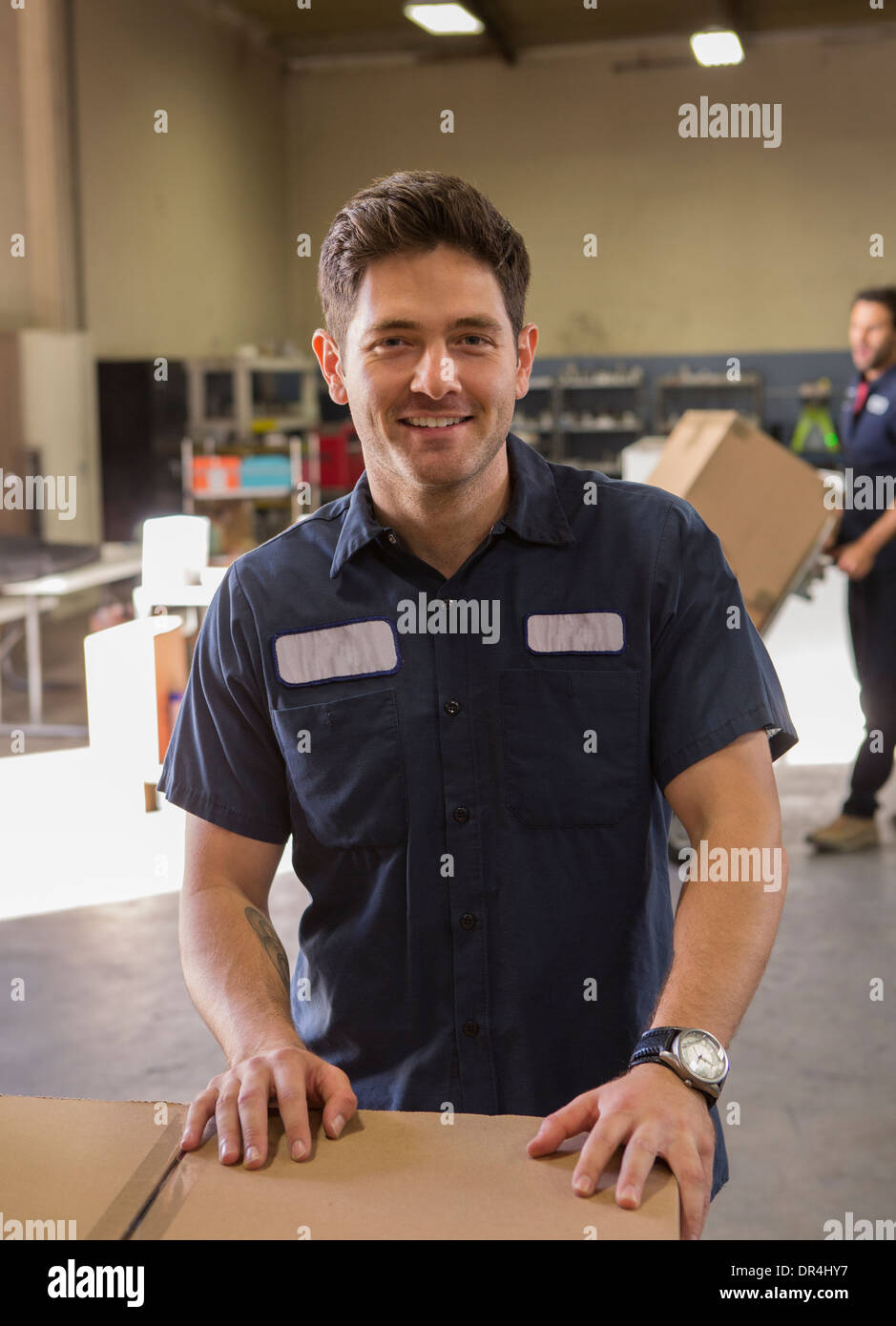 Worker smiling in warehouse Stock Photo - Alamy
