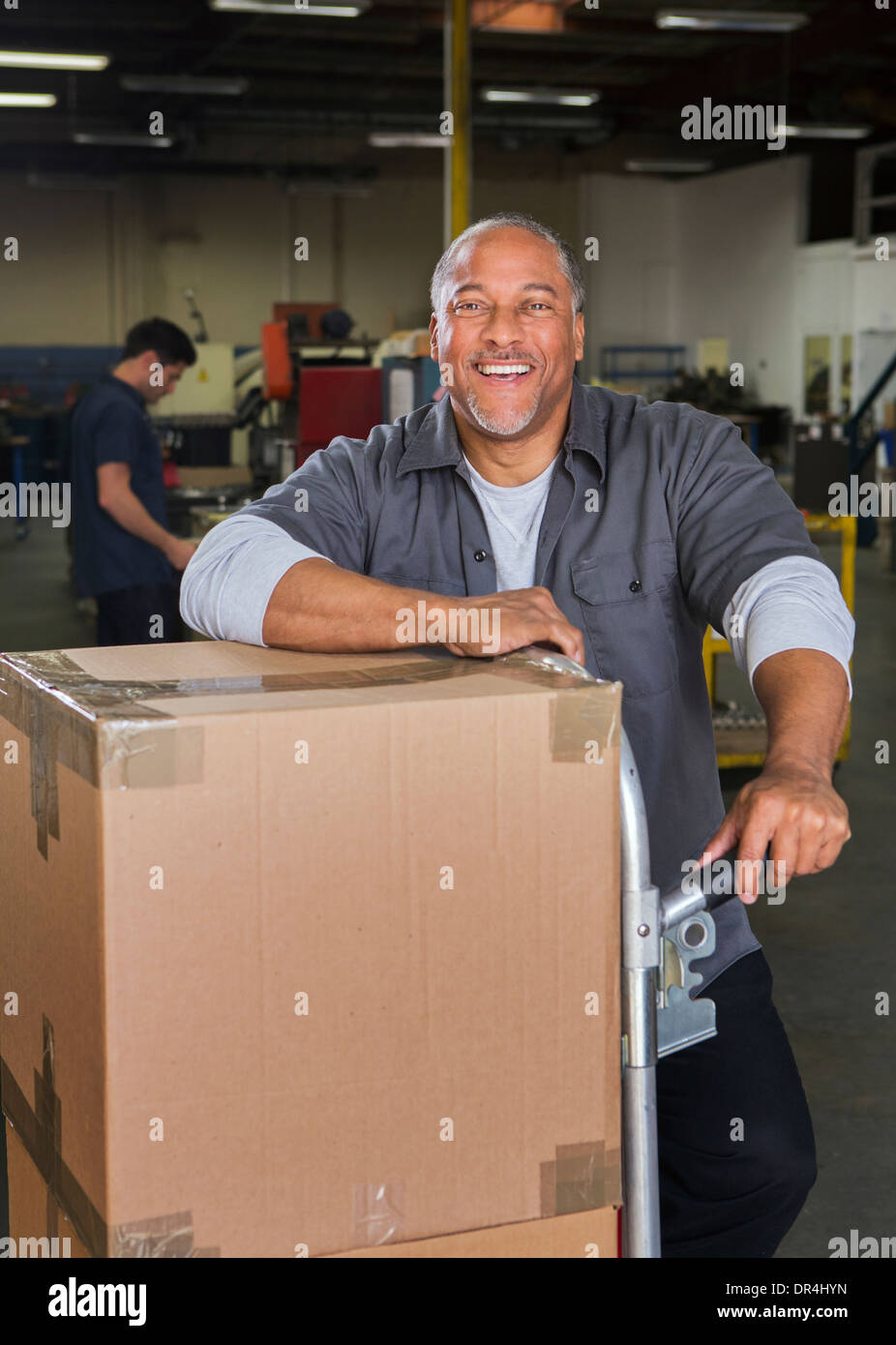 Worker smiling in warehouse Stock Photo - Alamy