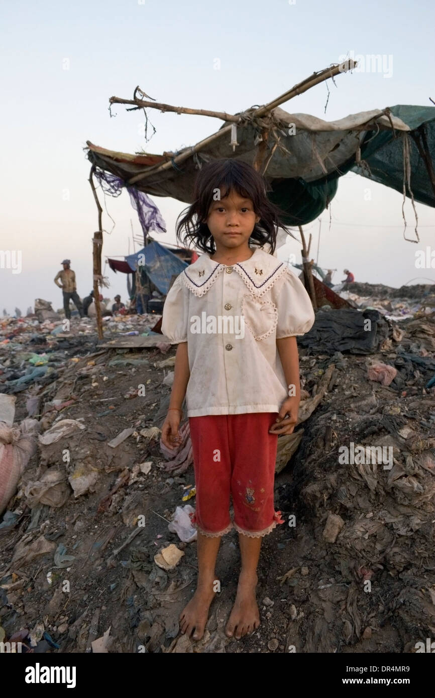 A young child laborer girl is standing near a ramshackle shelter at the ...