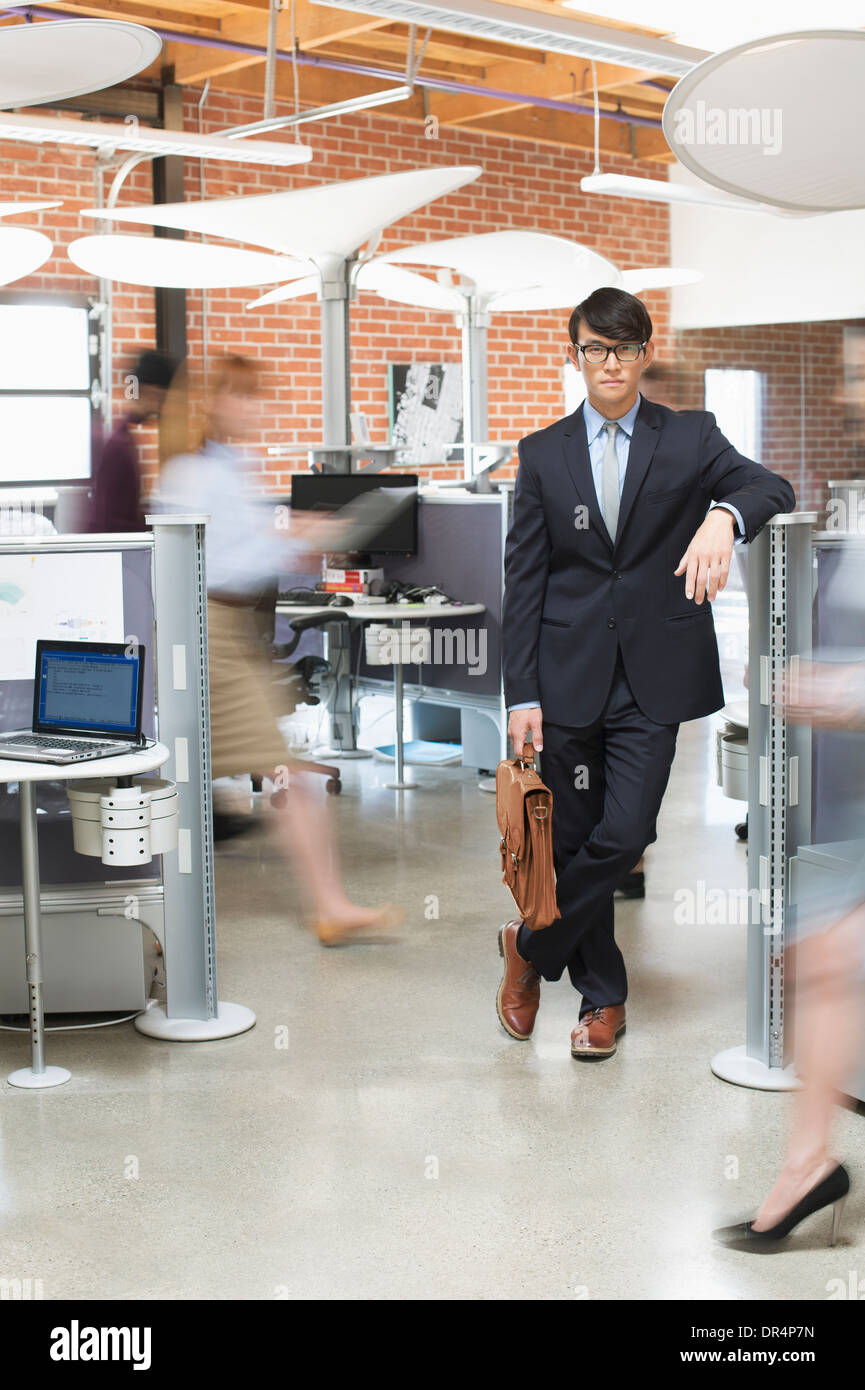 Businessman standing in busy office Stock Photo - Alamy