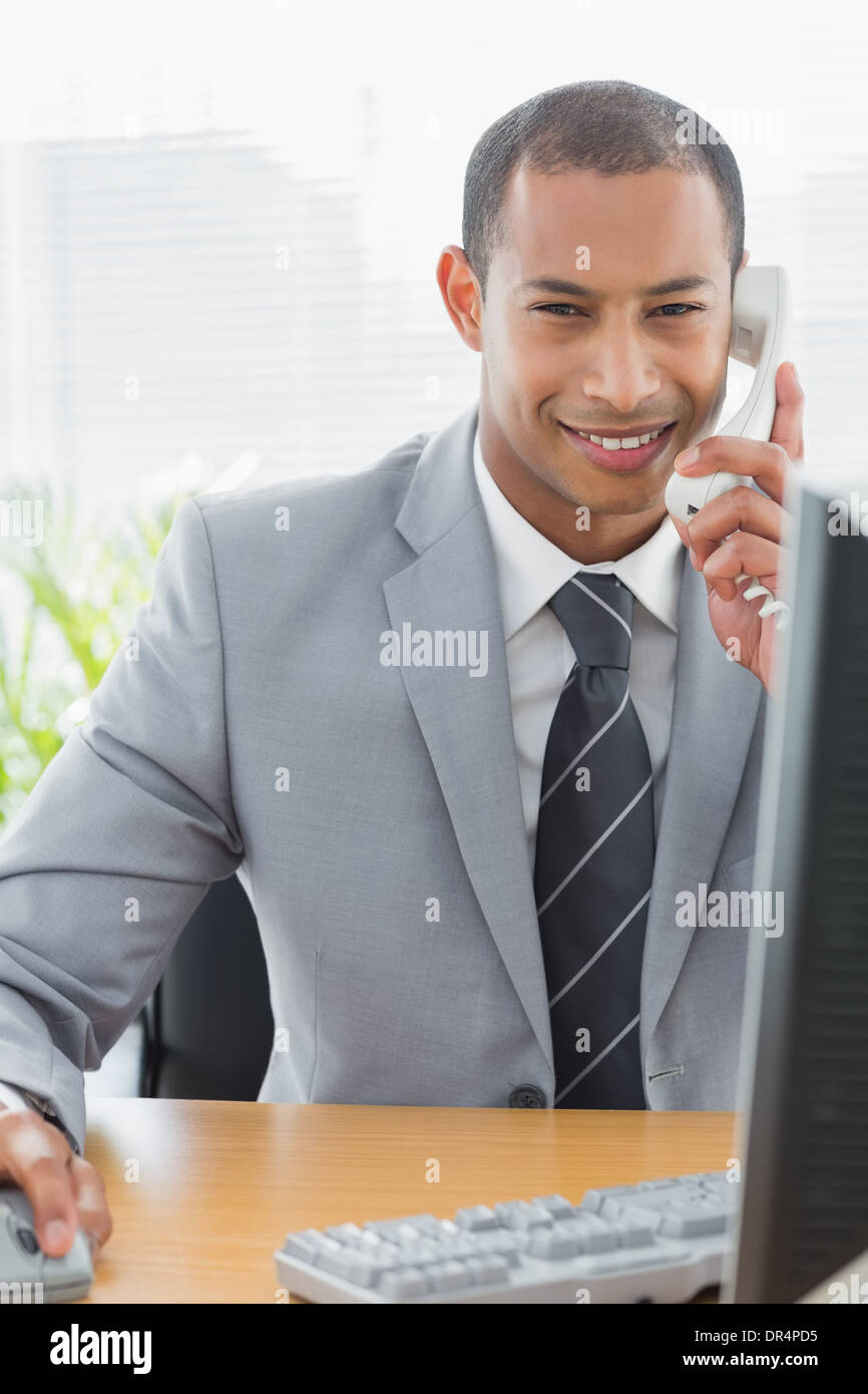 Businessman using computer and phone at office desk Stock Photo - Alamy
