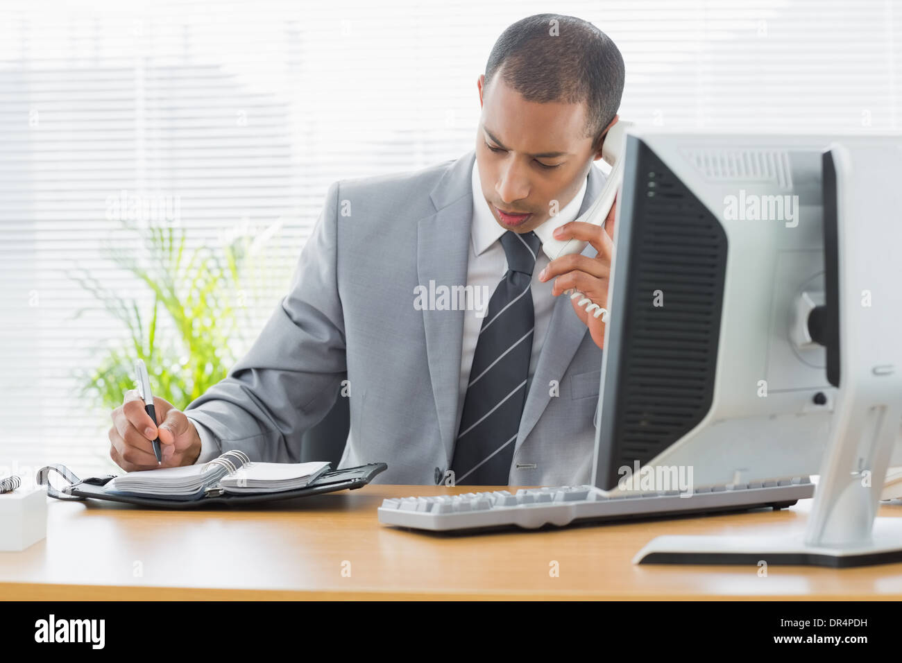 Businessman using computer and phone at office desk Stock Photo - Alamy
