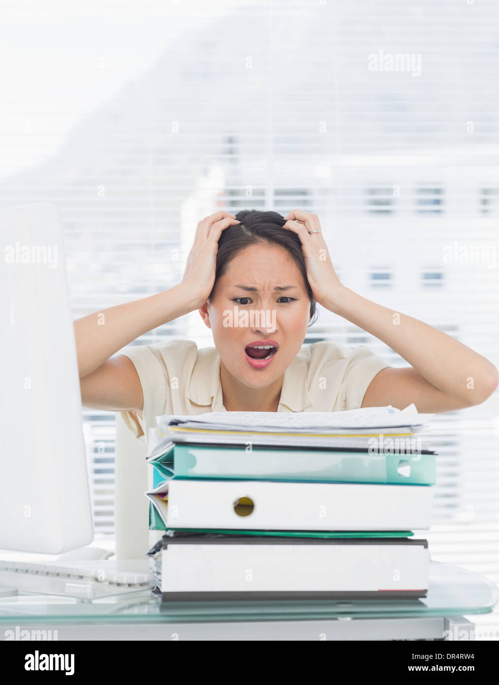 Angry businesswoman shouting with stack of folders at desk Stock Photo ...