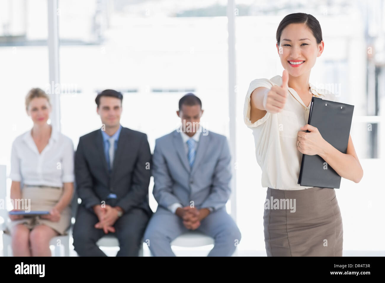 Woman gesturing thumbs up with people waiting for interview Stock Photo ...
