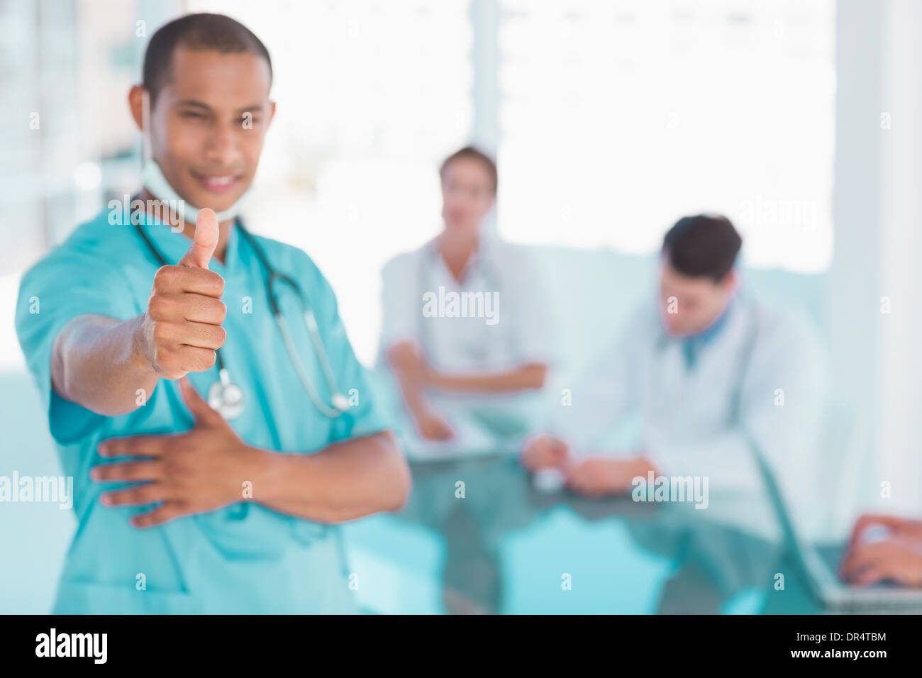 Surgeon gesturing thumbs up with group around table in hospital Stock ...