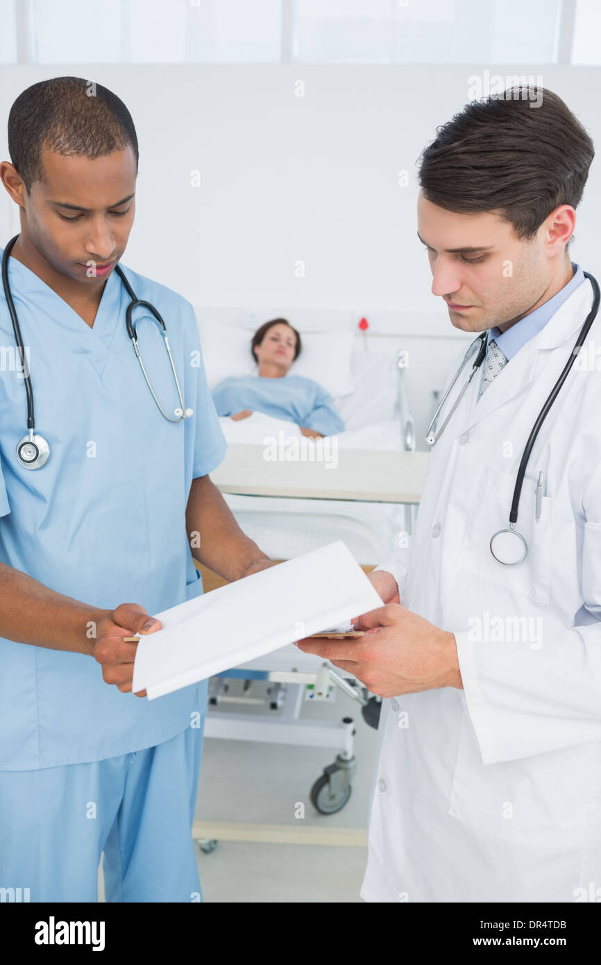 Doctors looking at reports with patient in hospital Stock Photo - Alamy