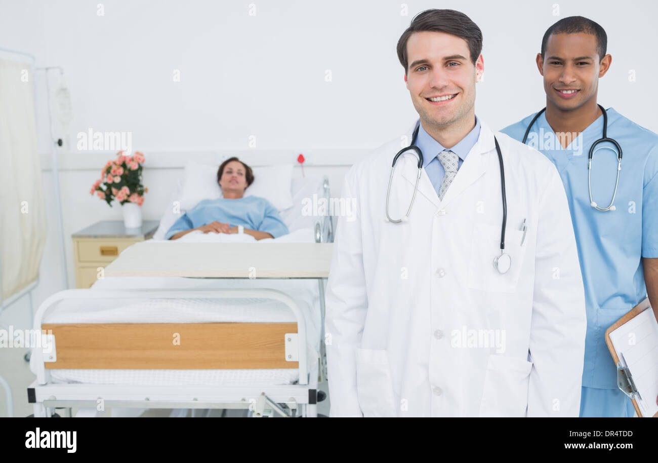 Two smiling doctors with patient in hospital Stock Photo - Alamy