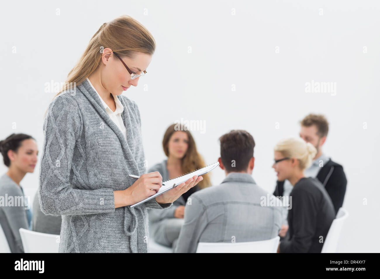 Therapist writing notes with group therapy in session Stock Photo - Alamy