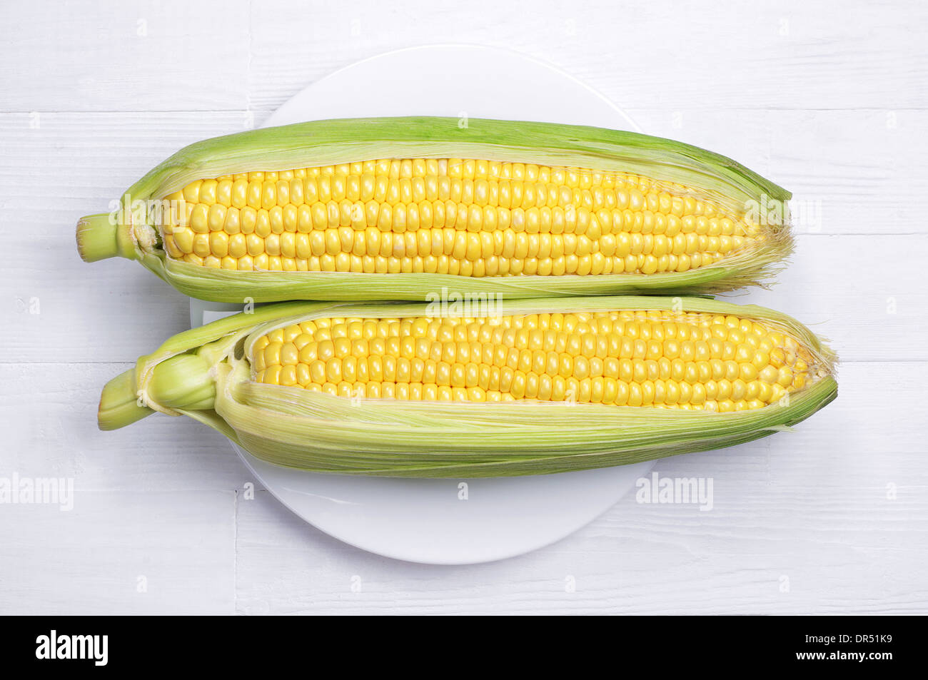 Two raw corns on white table. Top view Stock Photo - Alamy