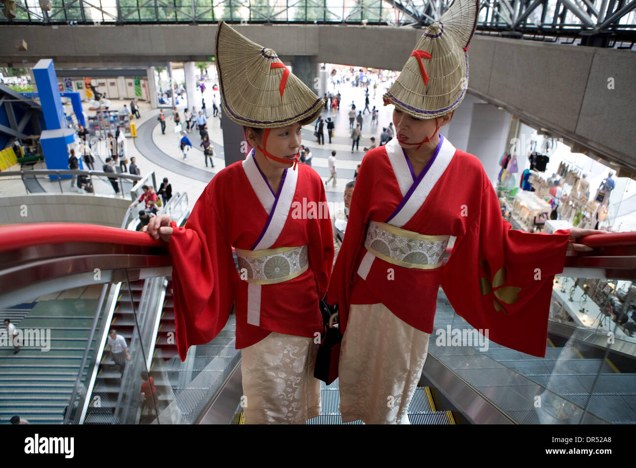 Women wearing mirrored outfits ride up an escalator. Kimonos are the ...