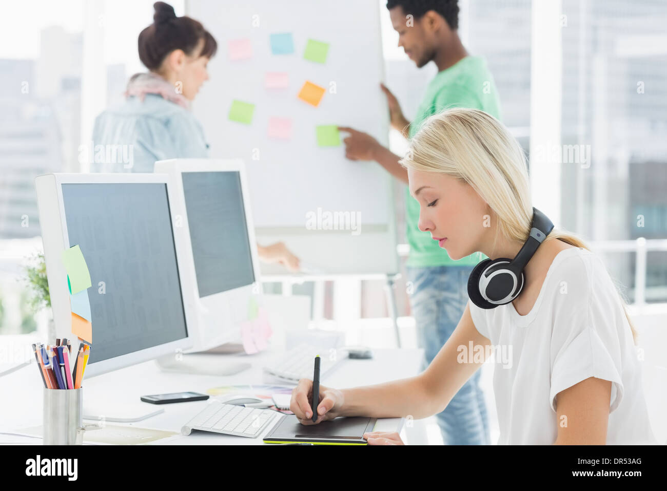 Artist drawing something on graphic tablet with colleagues behind at ...