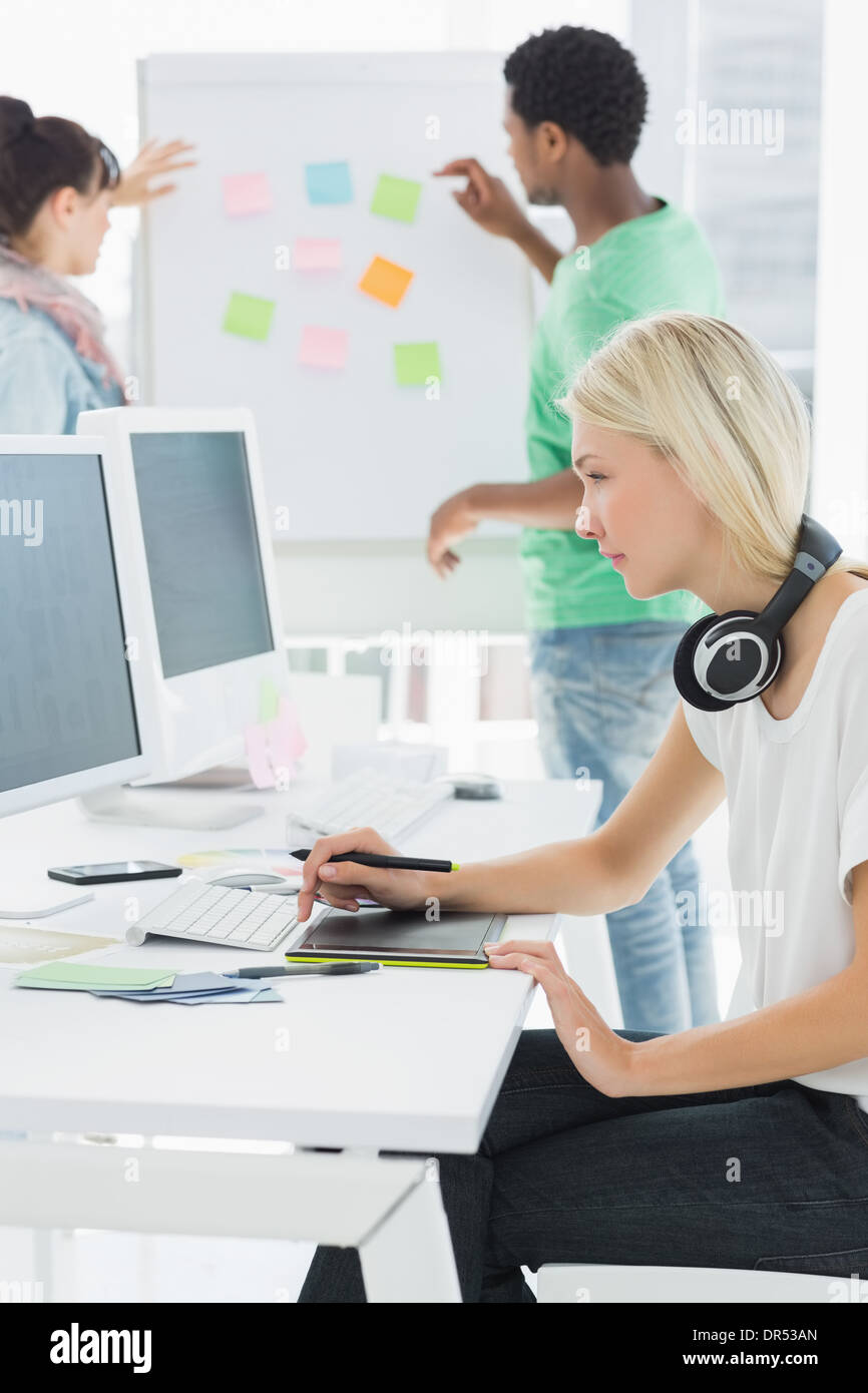 Artist drawing something on graphic tablet with colleagues behind at ...